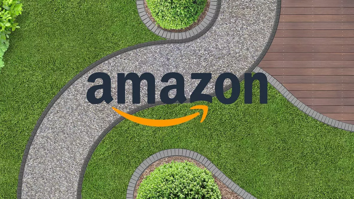 Un logo Amazon sopra un marciapiede che si snoda attraverso un giardino.