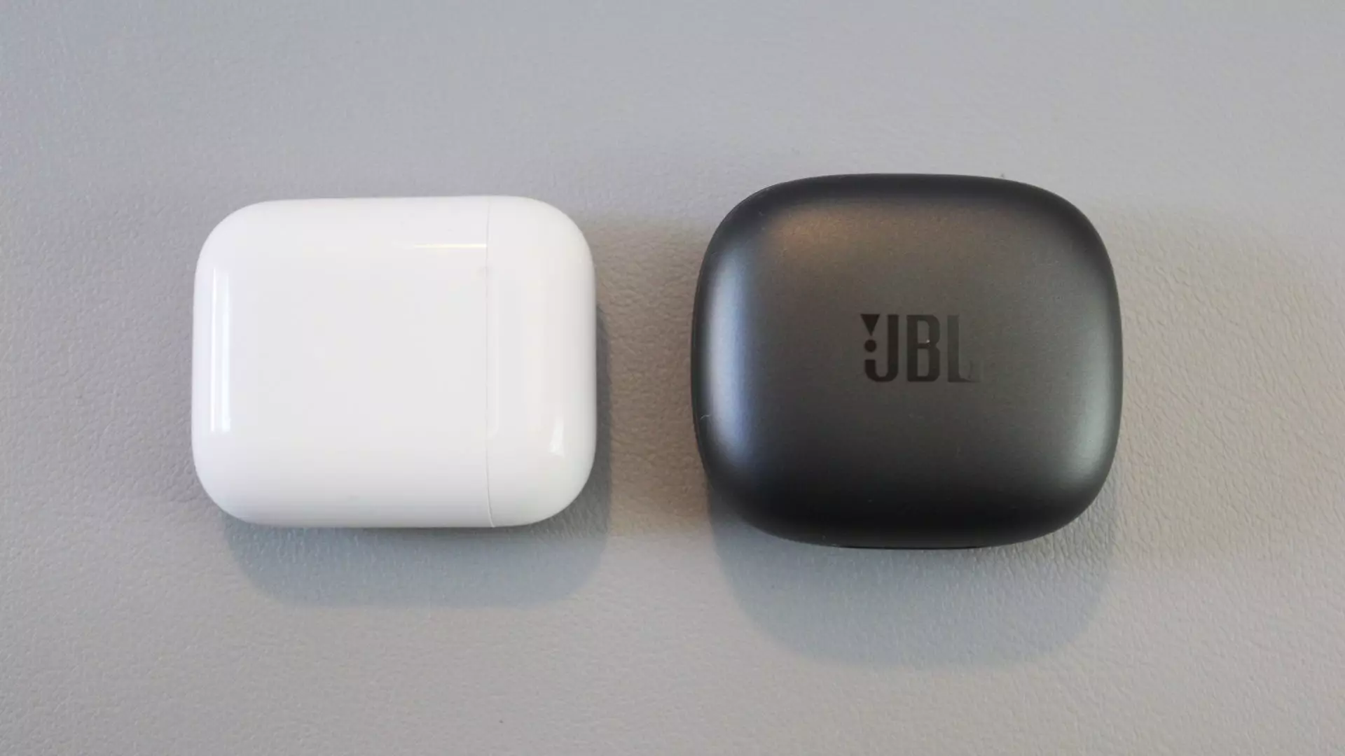 შედარებისთვის, Apple AirPods-ის ქეისი JBL ყურსასმენების ყუთის გვერდით