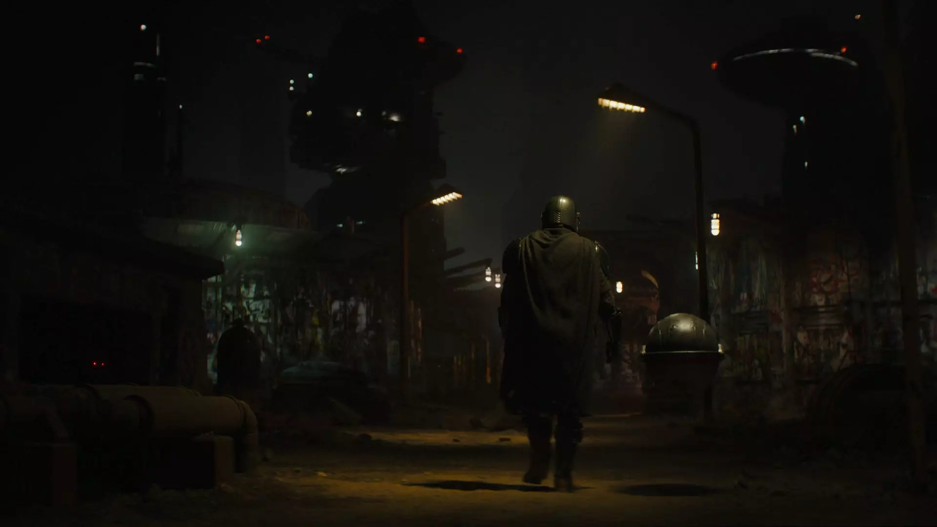O Mandaloriano andando por uma cidade escura e suja.