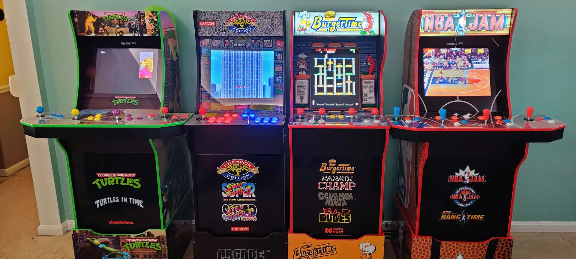 Четыре автомата Arcade1Up стоят в ряд, все с почти одинаковыми профилями.
