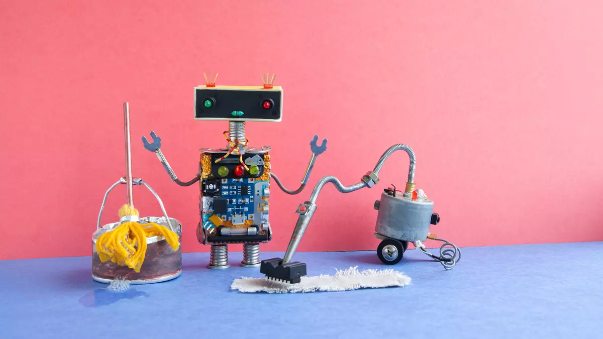 Rotaļlieta robotam, kas stāv blakus putekļsūcējam un mopam