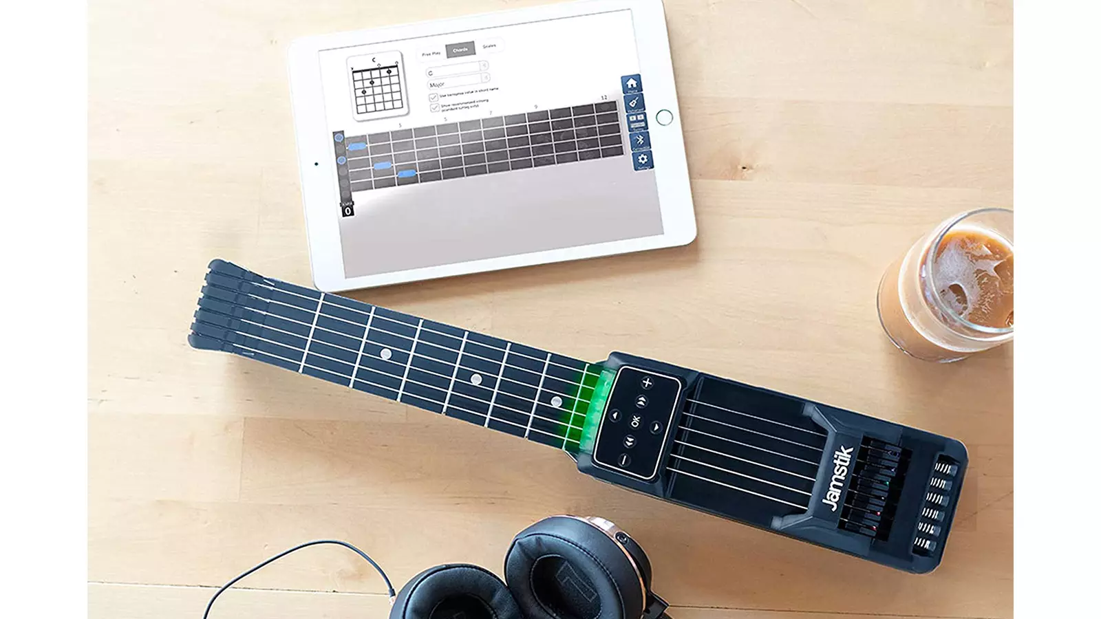 Jamstik Guitar Trainer na mesa com tablet e caneca de café e fones de ouvido
