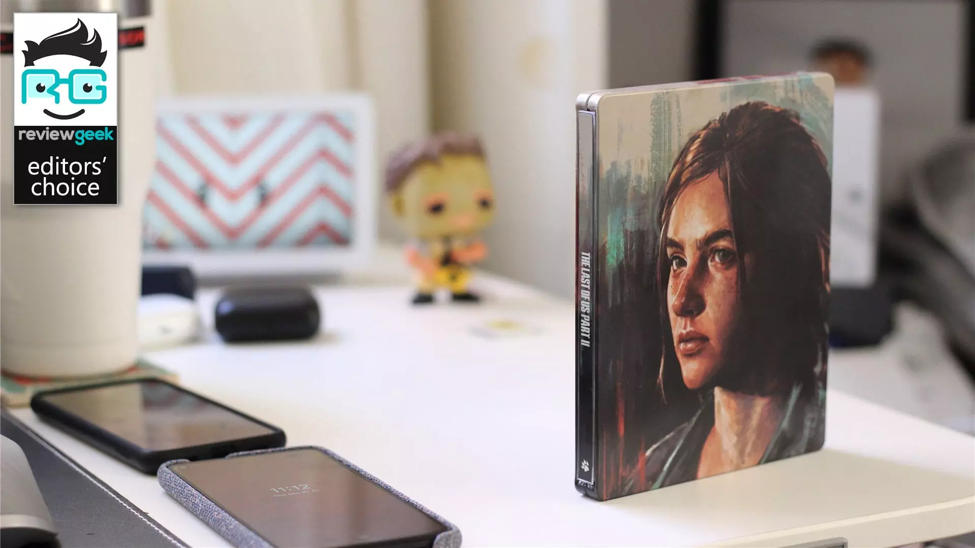 Limited Edition Last of Us Part II -kotelo valkoisella työpöydällä, Nest Hub ja Funko Pop taustalla