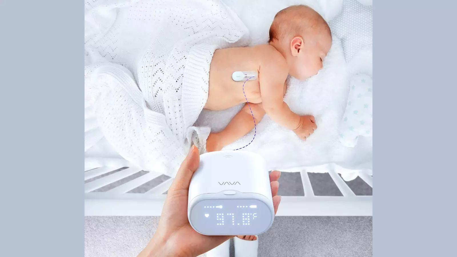 Roditelj drži čitač termometra dok gleda bebu u krevetiću