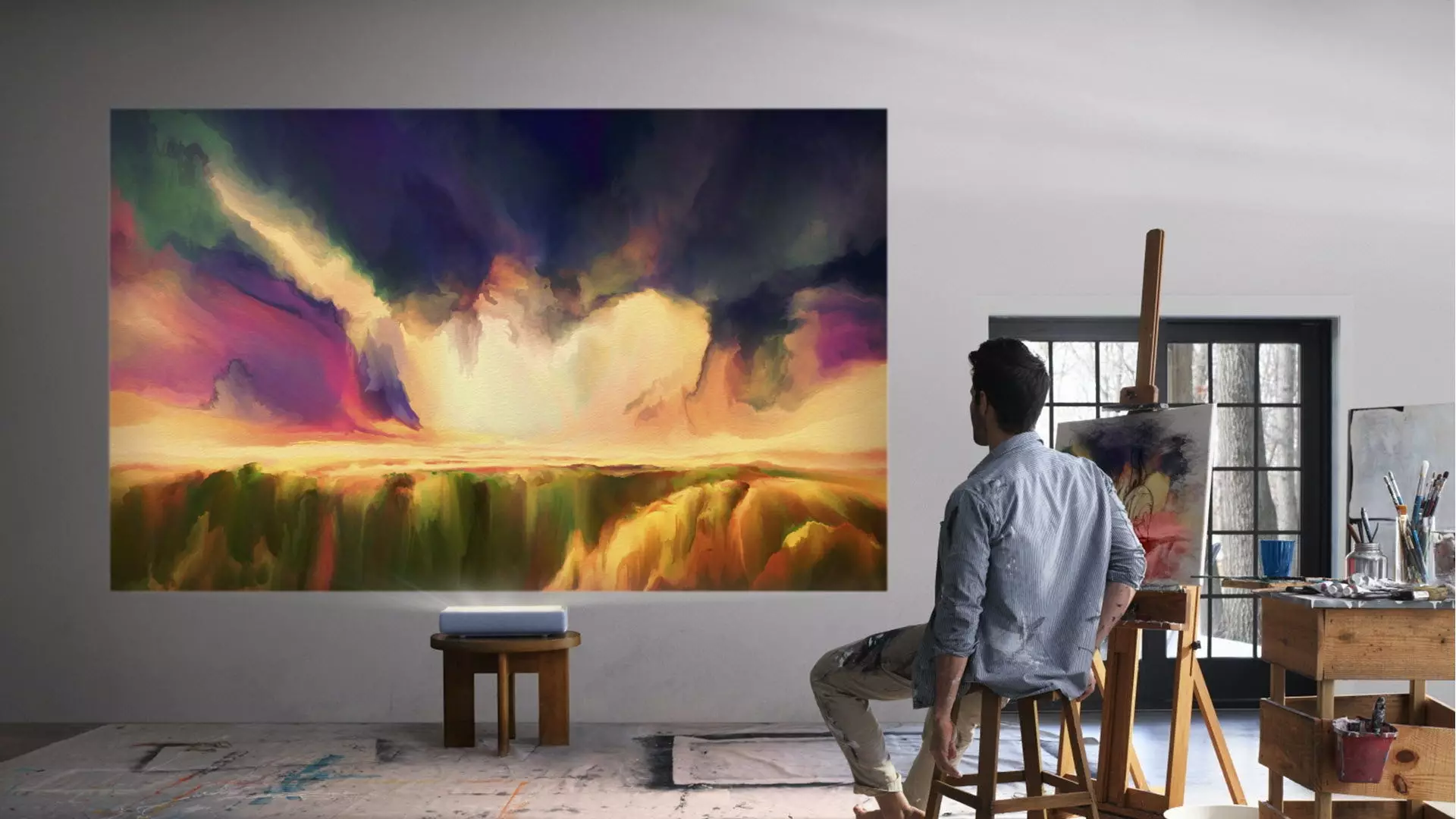 Um homem olhando para uma pintura gigante projetada em uma parede.