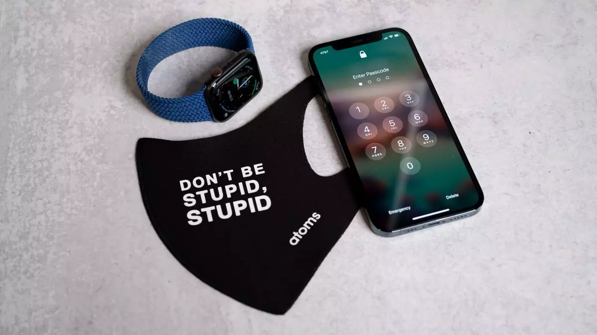 Apple Watch dan iPhone di sebelah topeng muka.