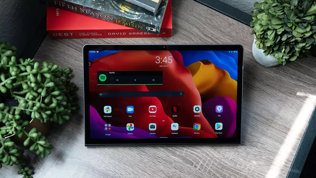 D'Lenovo Yoga Tab 11 mat Écran op weist Apps, op Dësch nieft Bicher a Planzen gesat