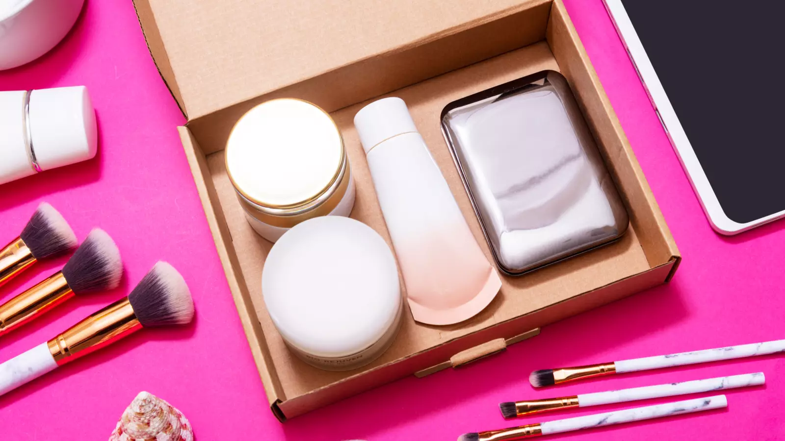 Tablet digital sareng kotak langganan makeup dina méja pink