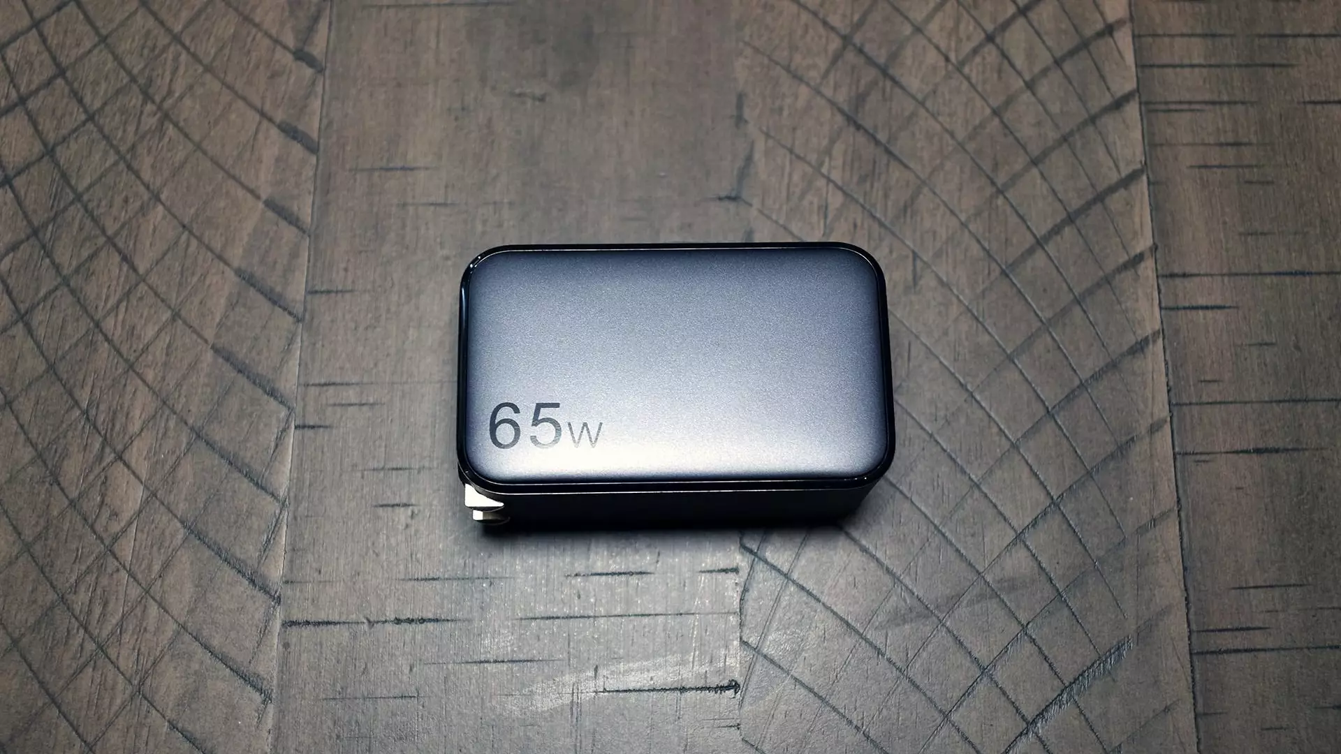 UGREEN Nexode 65 W USB-C töltő egy asztalon ülve, a villái távol vannak