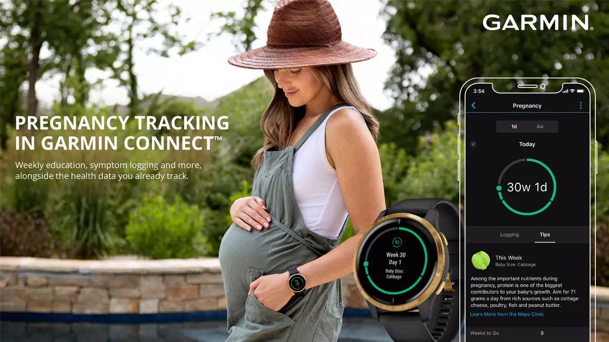 एक महिला अपने गर्भवती पेट को धारण करते हुए उह, एक रोमर पहनती है? जम्पर? मुझे यकीन नहीं है कि यह क्या है। नई गर्भावस्था ट्रैकिंग सुविधाओं को दिखाने के लिए एक गार्मिन घड़ी और कनेक्ट ऐप एक तरफ हैं