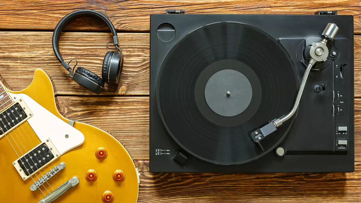E-Gitarre, Kopfhörer und Plattenspieler mit Vinyl auf Holzhintergrund