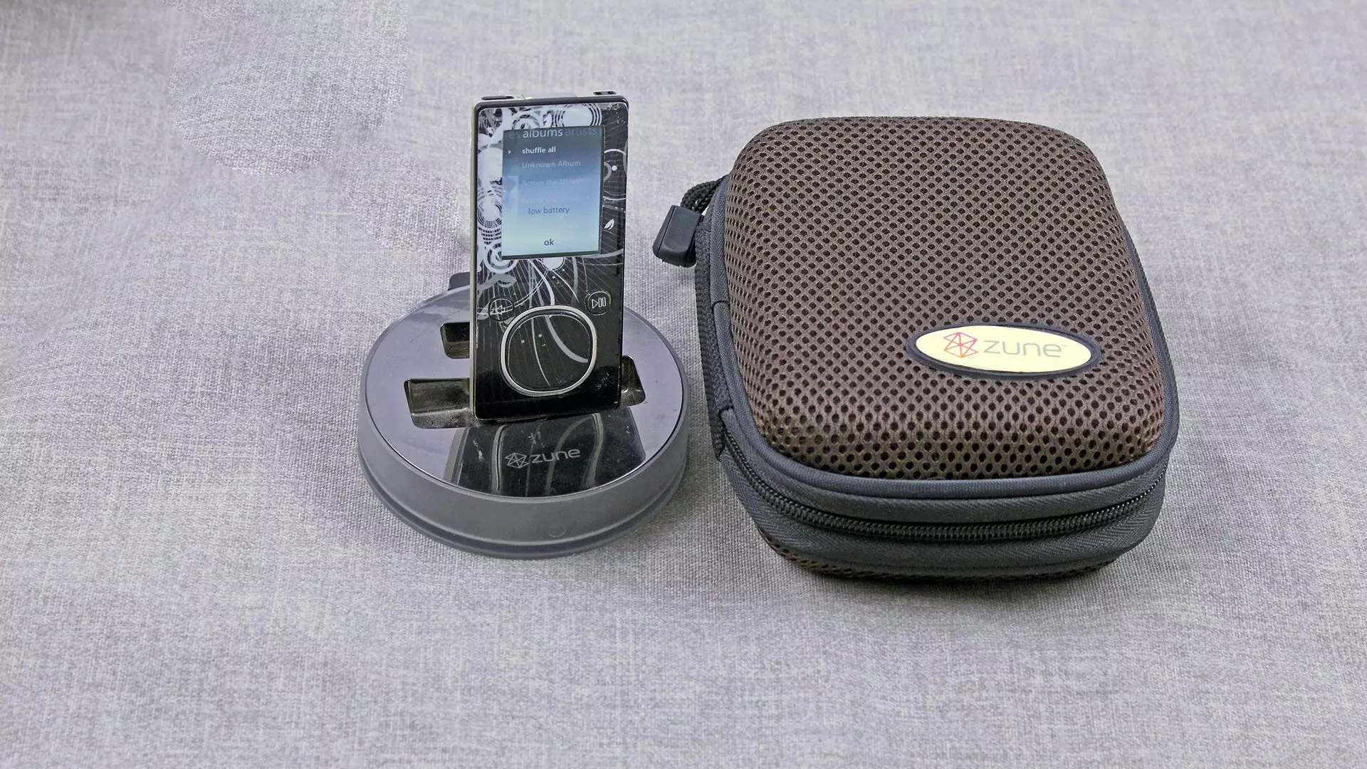 Usa ka MIcrosft Zune sa usa ka branded dock, sunod sa usa ka Zune branded speaker.