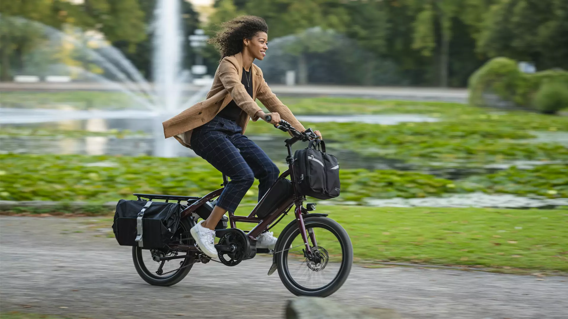 Person som kjører Quick Haul e-sykkel gjennom en frodig park, med en bag lastet på den