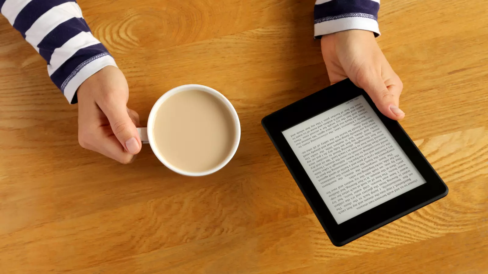 ადამიანი კითხულობს რომანს Kindle-ზე და სვამს ყავას.