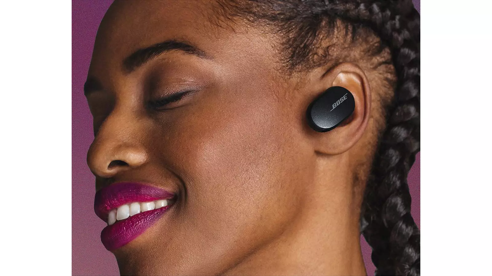 Маладая жанчына носіць новыя навушнікі Bose QuietComfort Earbuds на ружовым фоне