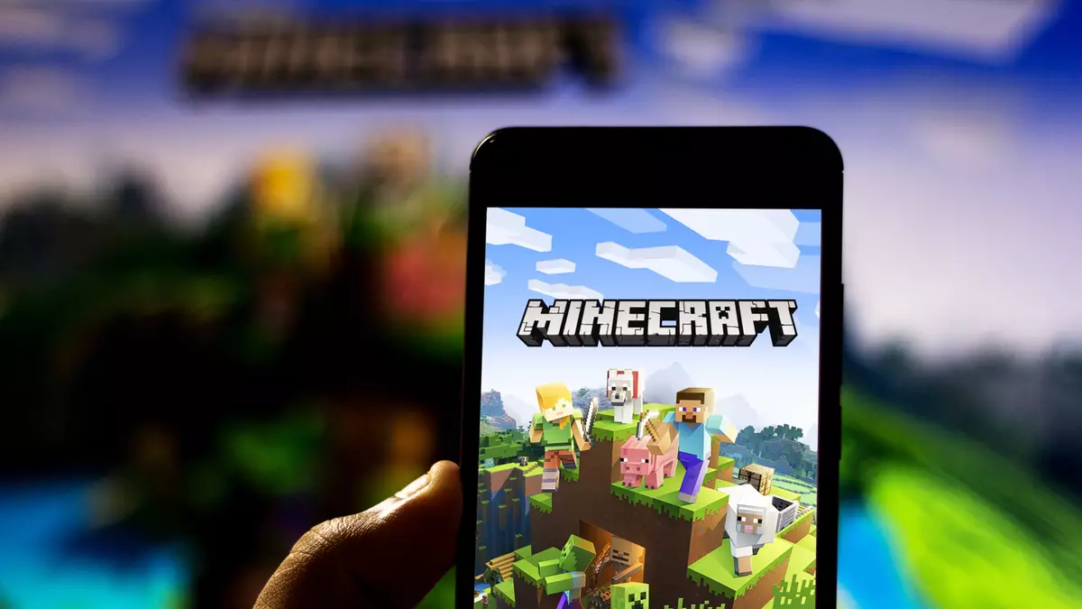 Logo Minecraft na mobilním zařízení Android, držené před televizí s načtenou hrou