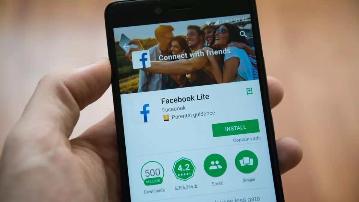 Рука трымае тэлефон з загружанай праграмай Facebook Lite