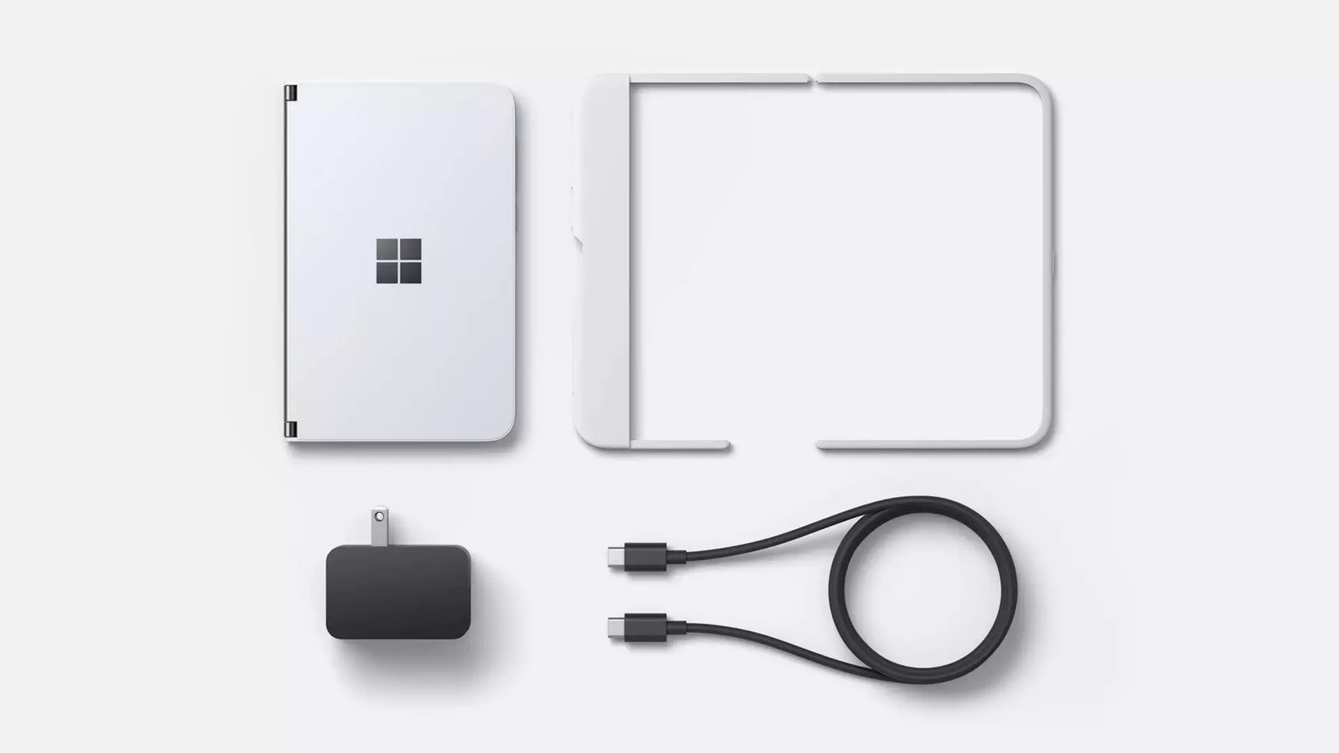 Το τηλέφωνο Surface Duo, ένα καλώδιο φόρτισης και τούβλο και μια θήκη προφυλακτήρα.