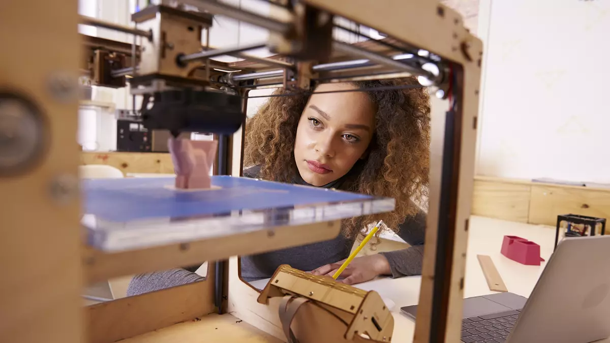 Хуванцар загвар бүтээхийн тулд 3D принтер ашиглаж буй хүн.