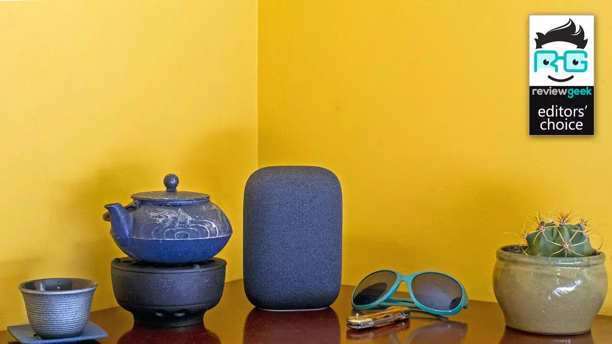 Een Nest Audio bij een theepot, kopje, zonnebril en plant op een nachtkastje.