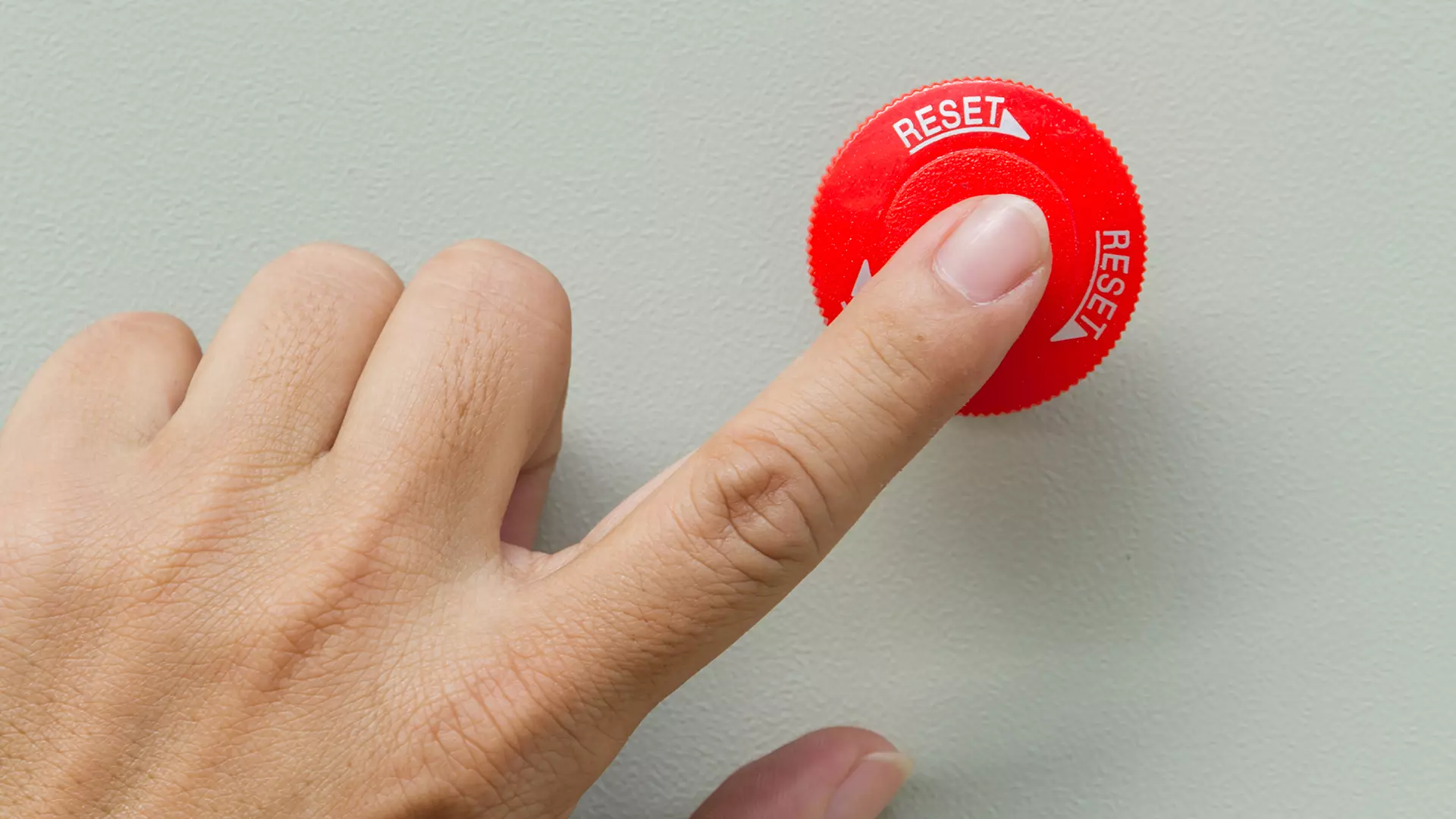 ایک انگلی سرخ ری سیٹ بٹن کو دباتی ہے۔