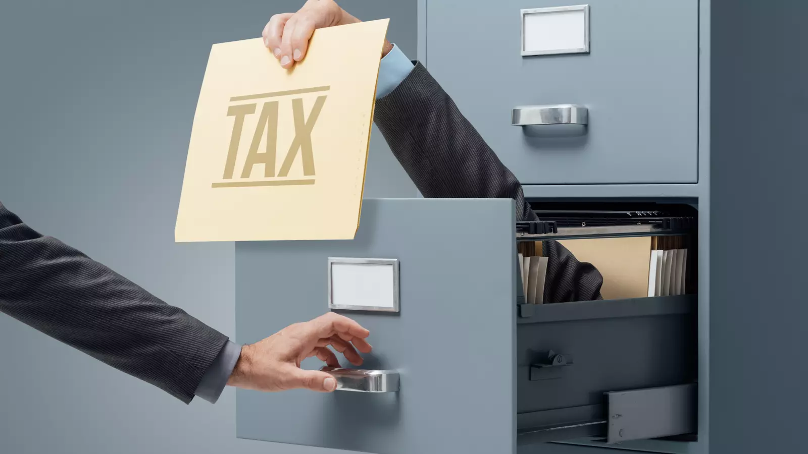 تاجری که در داخل یک کابینت بایگانی پرونده مالیاتی را به یک کارمند اداری می دهد
