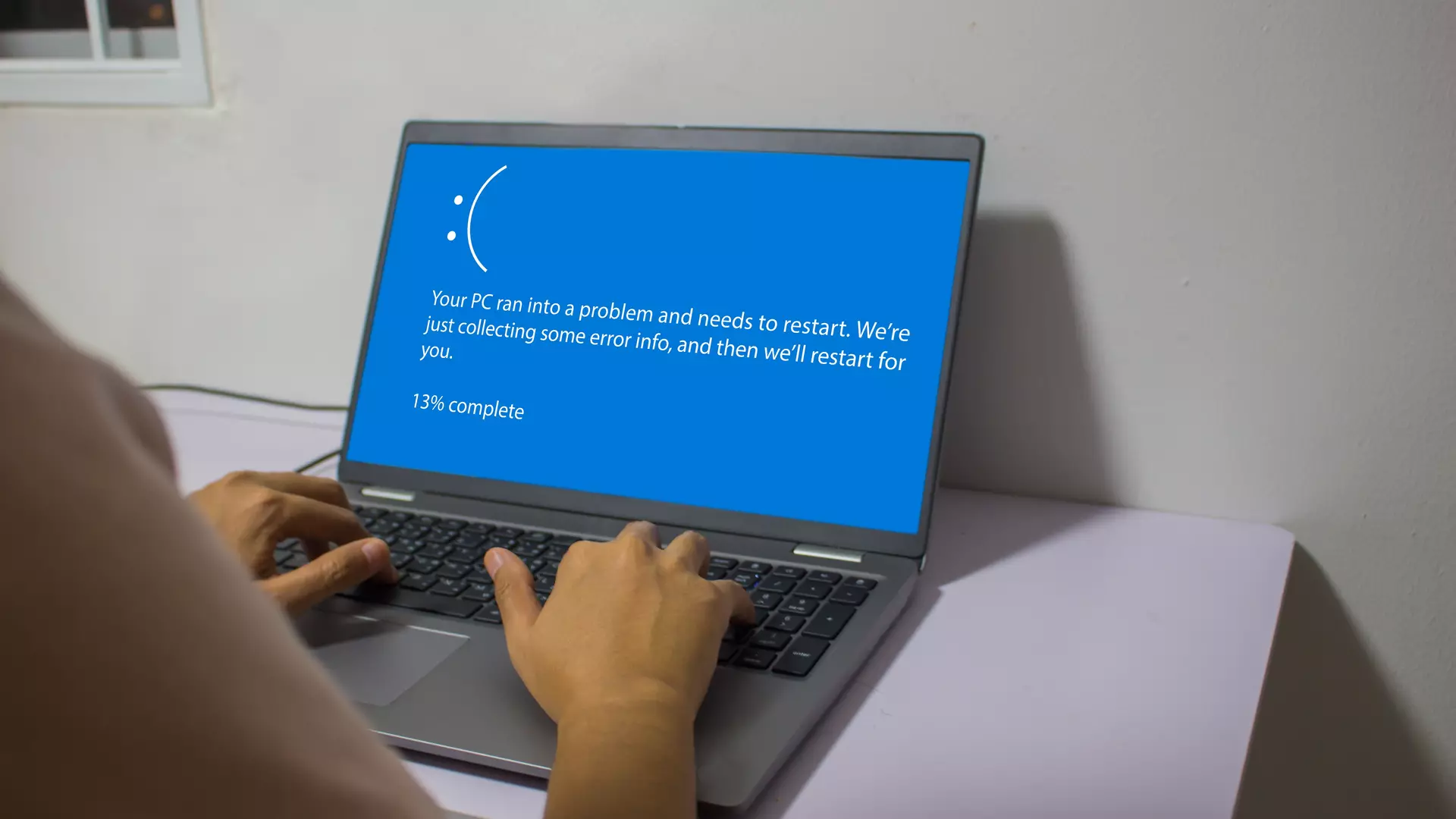 Un home que intenta utilizar un ordenador cunha pantalla azul da morte