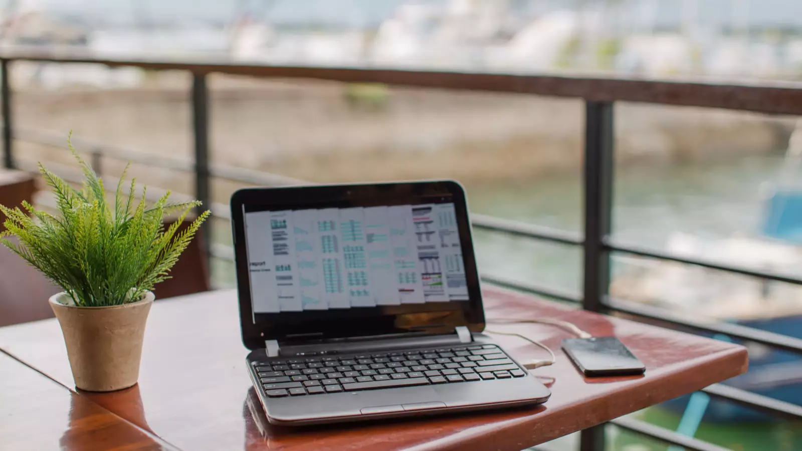 Laptop di atas meja kayu di kafe klub kapal pesiar dengan bisnis online melalui tethering hotspot WiFi