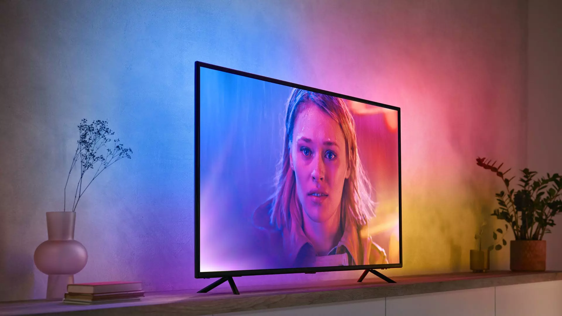 Sebuah TV dengan beberapa warna lampu warna yang berbeda bersinar dari belakang.