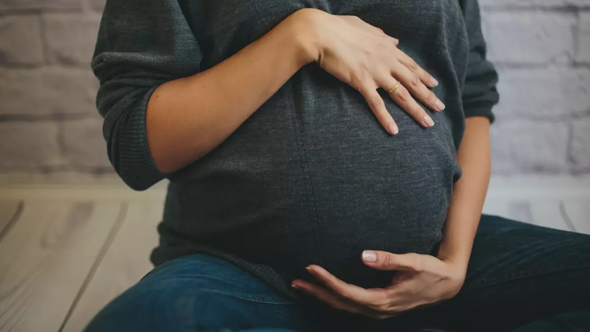 एक गर्भवती महिला अपने बच्चे के पेट को पकड़े हुए।