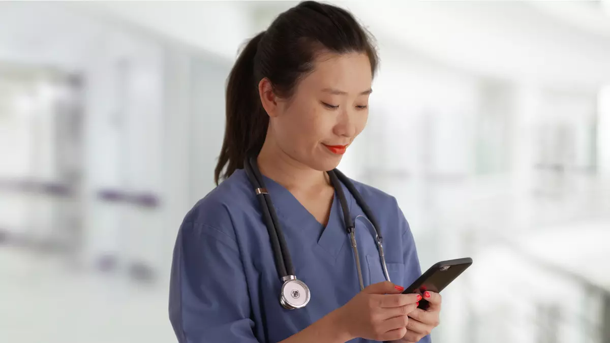 En Dokter kuckt op hirem Smartphone.
