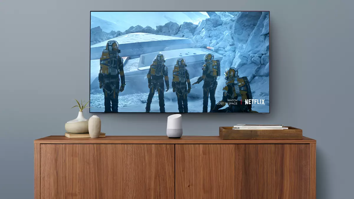 Un Google Home sur un meuble TV sous un téléviseur diffusant Netflix.