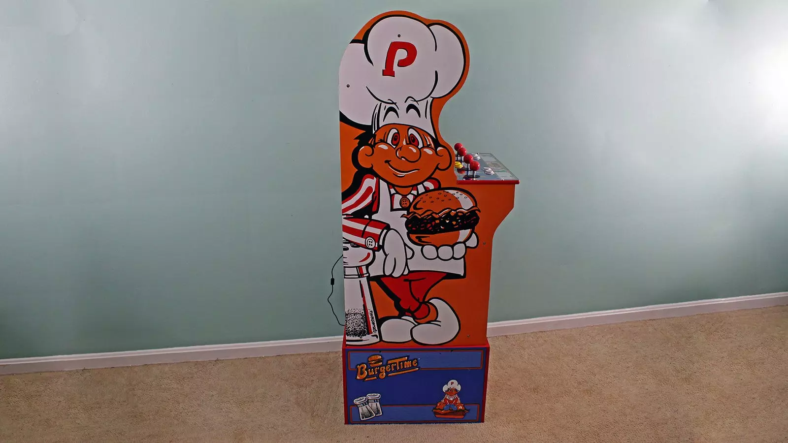 „Burger Time“ mašinos vaizdas iš šono, kuriame pavaizduotas šefo skrybėlės formos profilis.