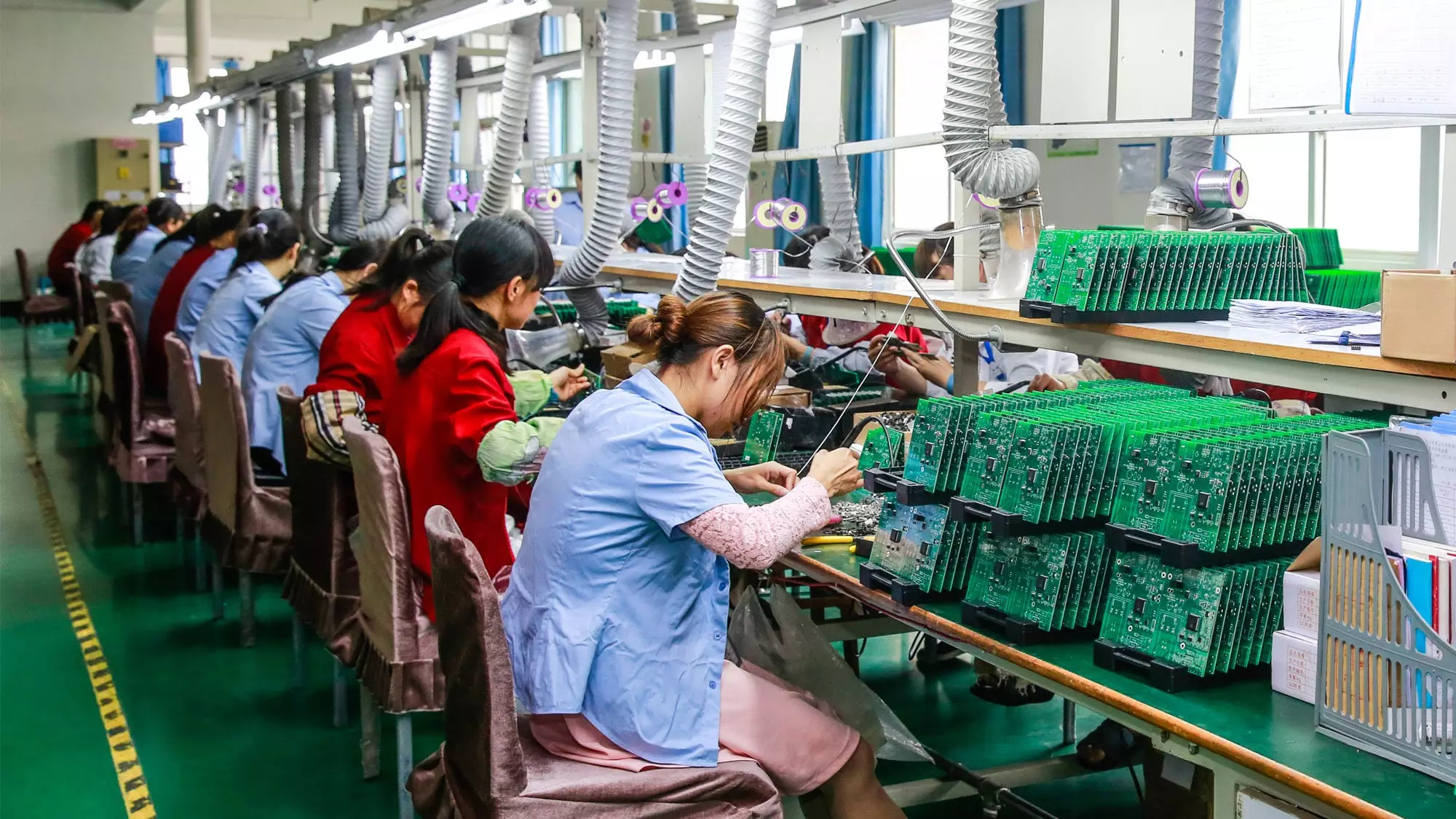 Работниците във фабриката в Дзянси произвеждат платки на поточна линия.