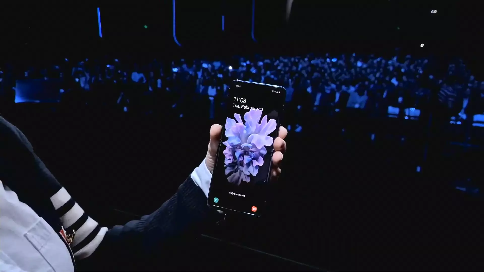 Seseorang yang memegang Galaxy Z Flip terbuka sepenuhnya dengan bunga pada paparan.