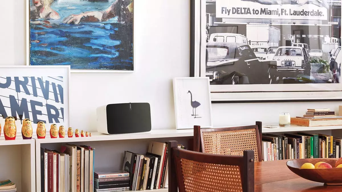 Sonos Play 5 на полица за книги покрај слики.