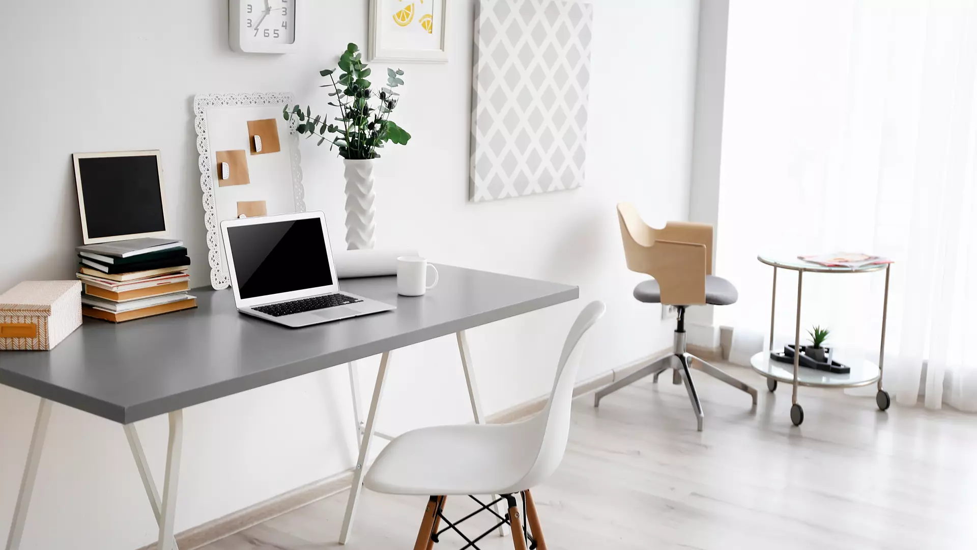 Čistý, väčšinou biely pracovný priestor s notebookom na stole