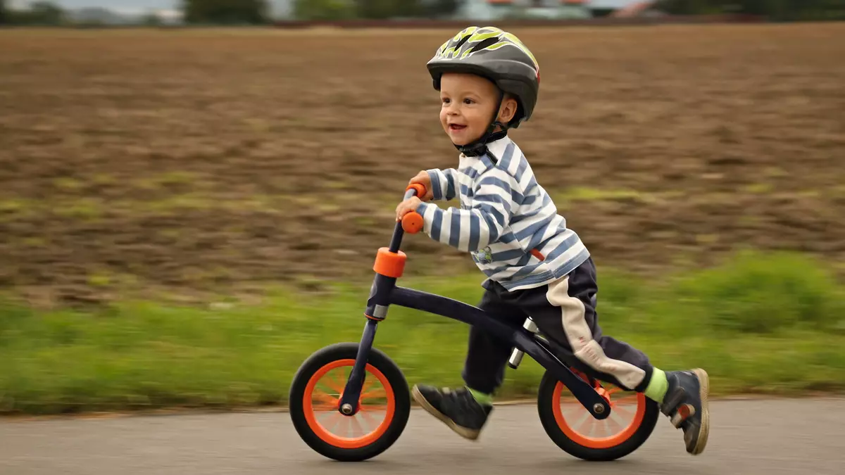 Un copil mic care merge pe o bicicletă de echilibru