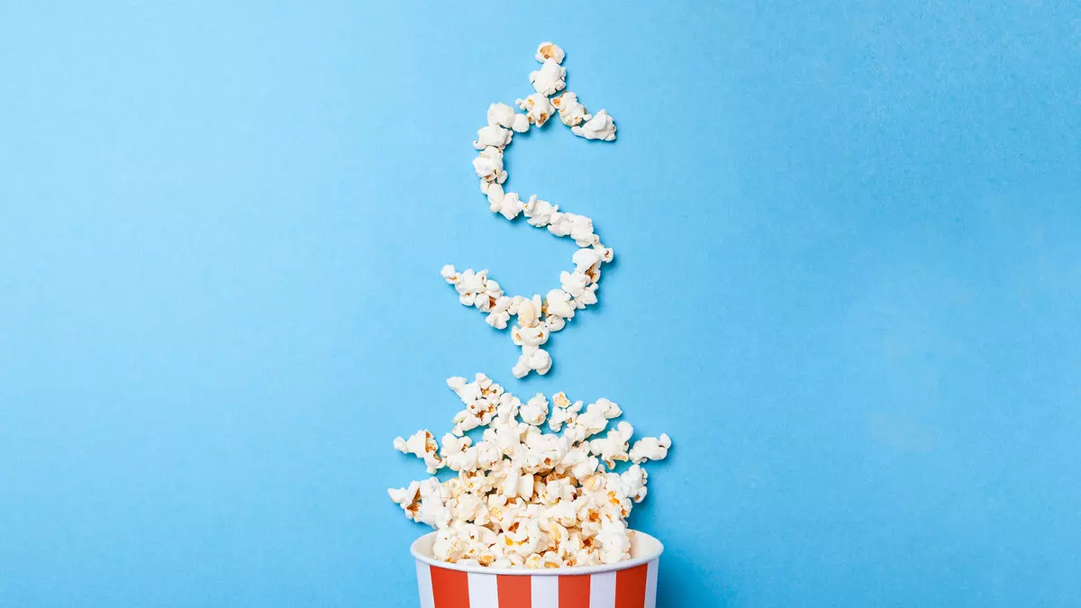 Eine Wanne Popcorn schwappt über, das Popcorn verwandelt sich in ein Dollarzeichen.