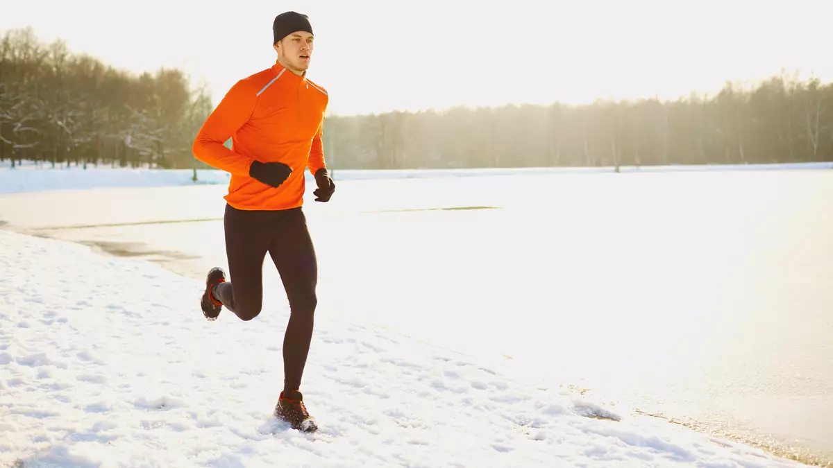 Młody mężczyzna biegający zimą w parku