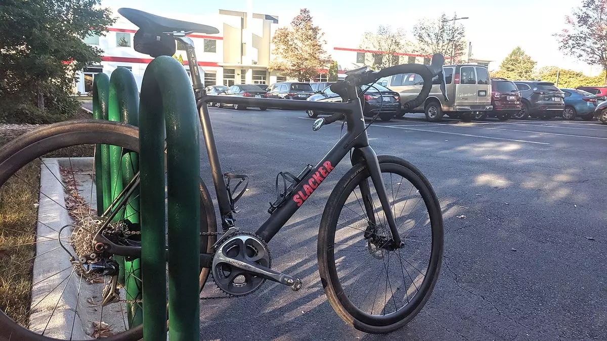Una bicicleta de cercanías en un portabicicletas en un estacionamiento.