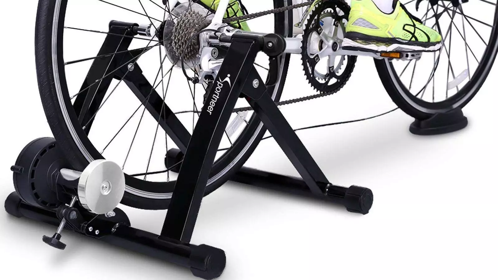 Sportneer Bike Trainer Statīvs ar piestiprinātu velosipēdu un cilvēka kājām uz pedāļiem.
