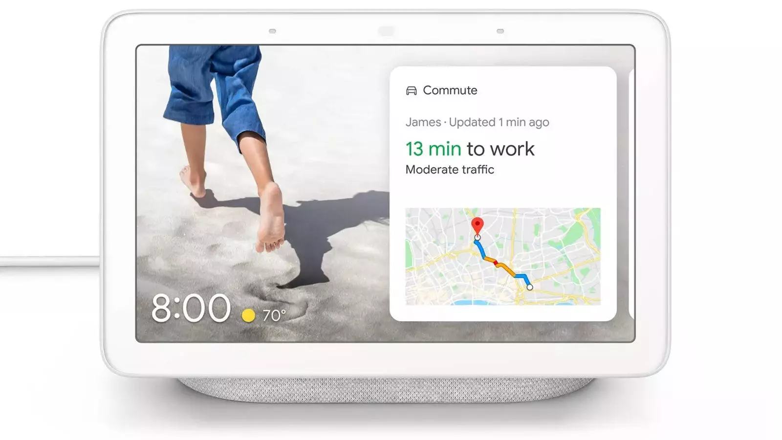 Un Google Nest Hub bianco che mostra la foto di una persona che cammina sulla spiaggia.