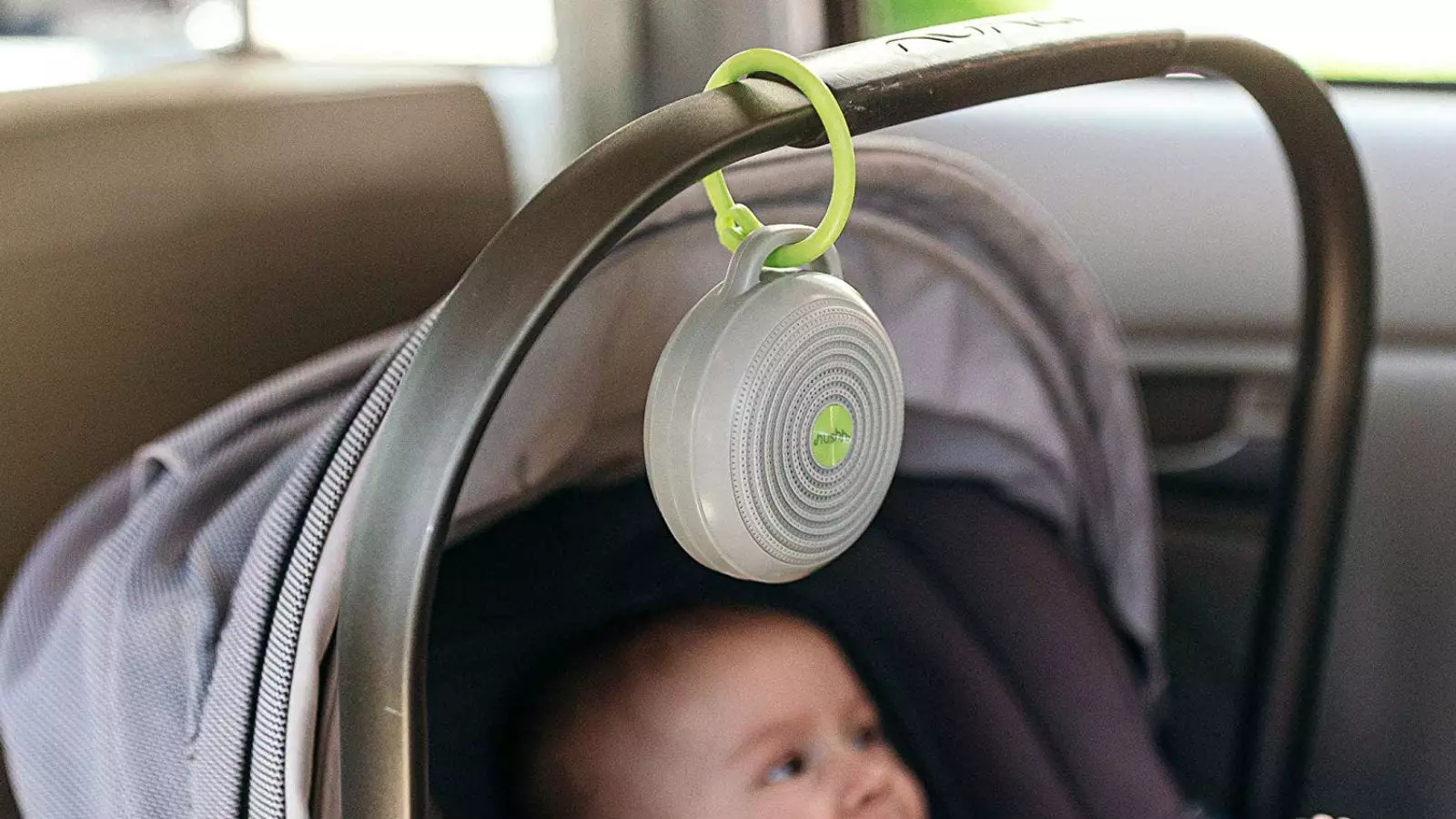 La machine à bruit blanc portable Marpac Hushh suspendue à une poignée de poussette au-dessus d'un bébé assis à l'intérieur.