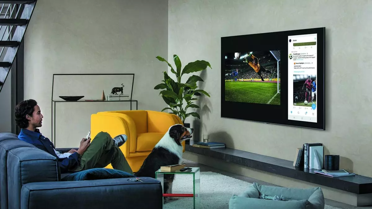 Isang lalaki at aso na nanonood ng malaking Samsung Q70T TV