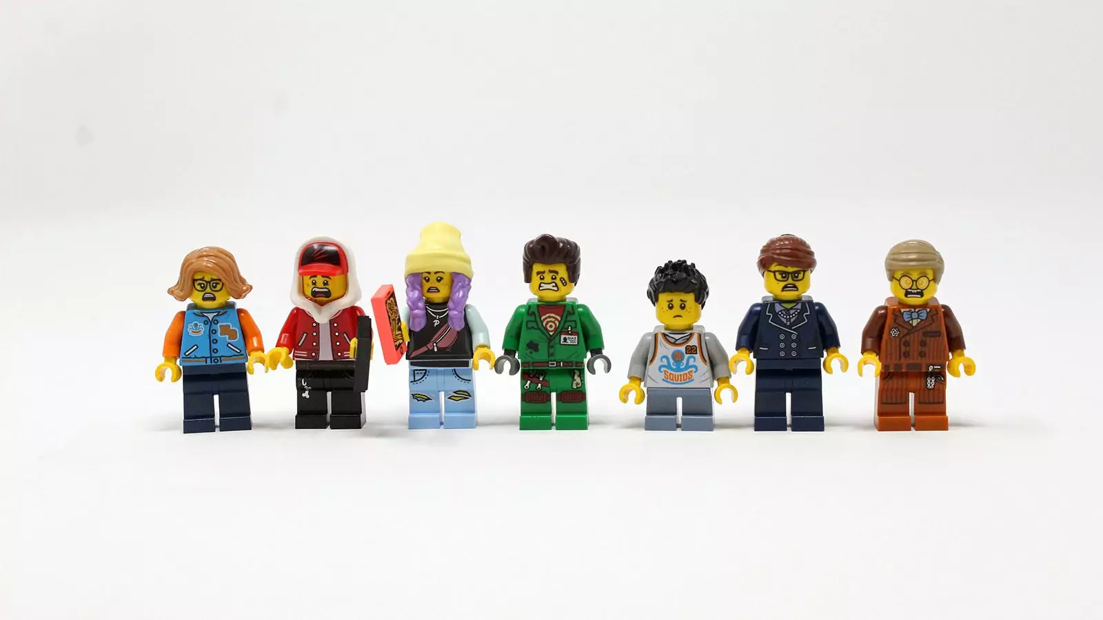 Sedem LEGO minifg, každá s komickým výrazom na tvári.