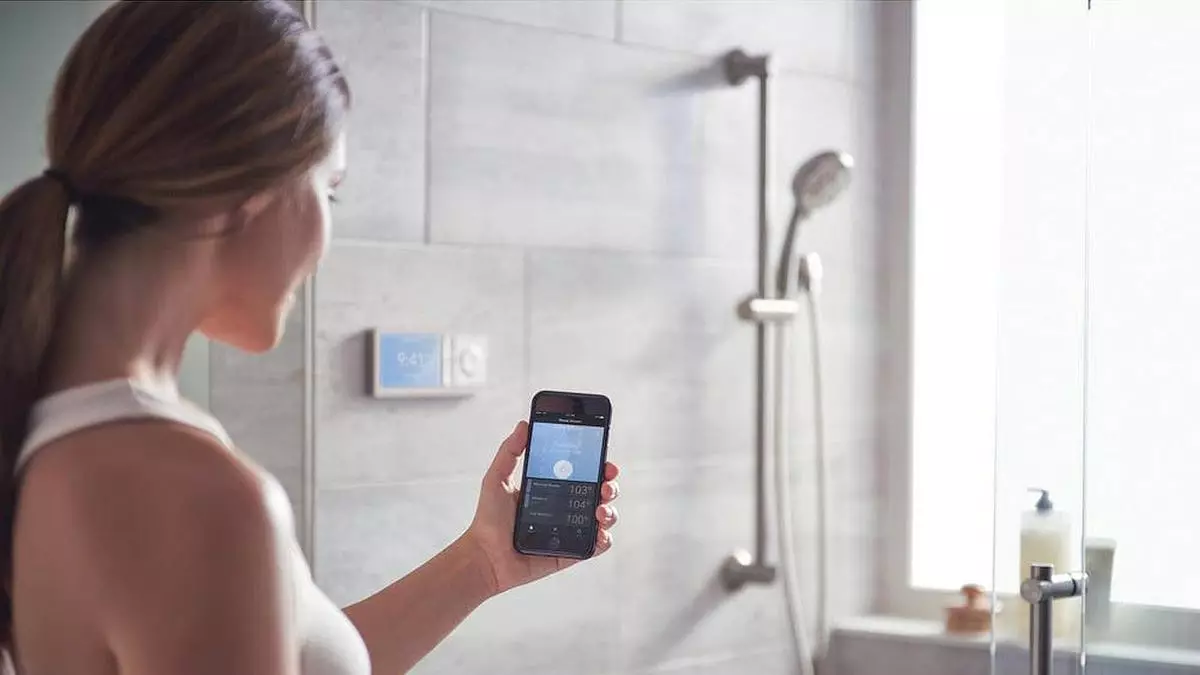 Žena ovládající svou sprchu pomocí smartphonu.