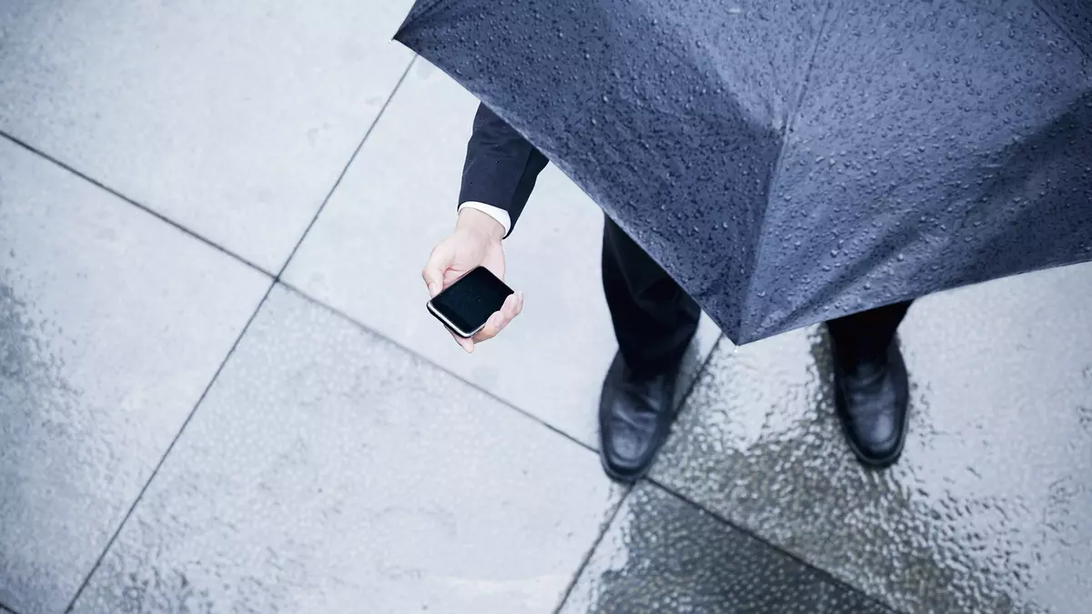 Um homem verifica seu telefone na chuva.