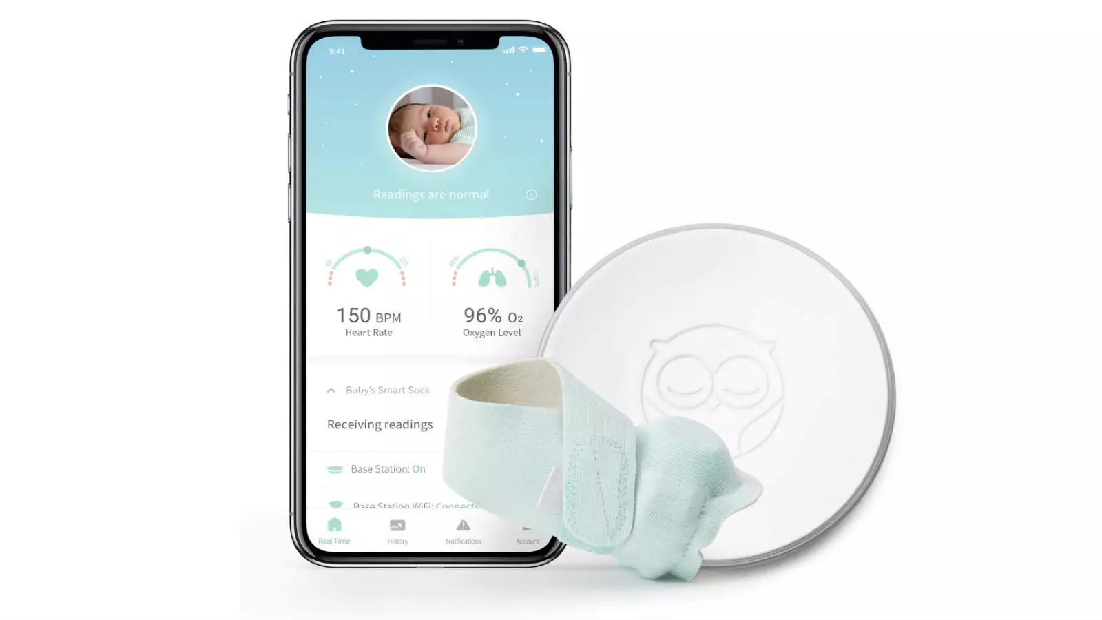 A aplicación Owlet nun teléfono intelixente que mostra a frecuencia cardíaca e o nivel de osíxeno dun bebé xunto ao monitor de bebé con calcetín intelixente Owlet.