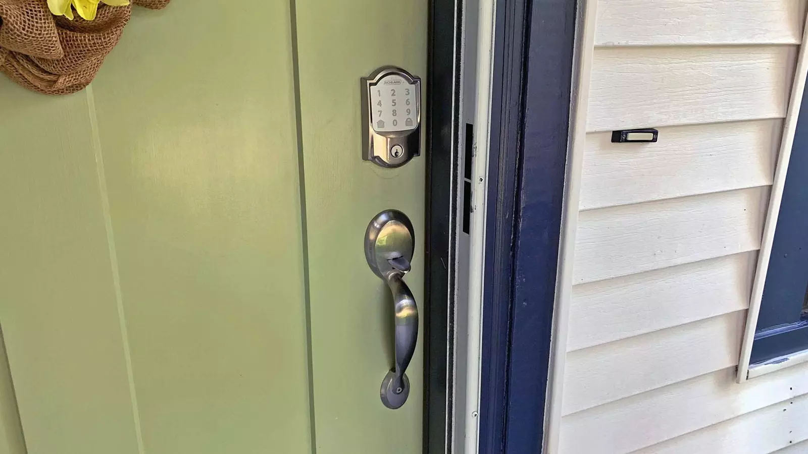 Zámok Schlage Encode nad zodpovedajúcou kľučkou dverí a inštalovaný vo dverách olivovej farby.